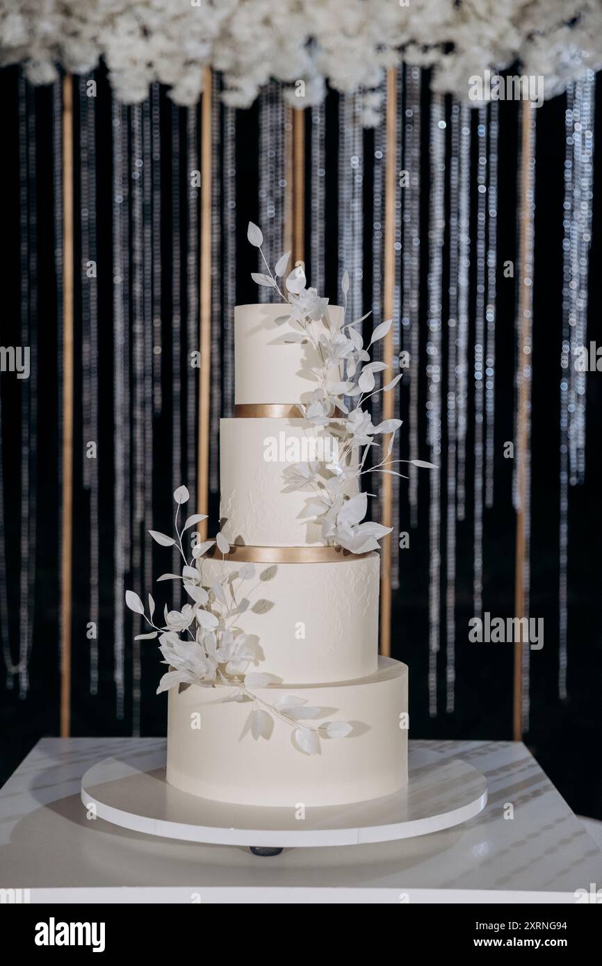 Wedding setup with three-tier white cake with floral accents. Wedding ...
