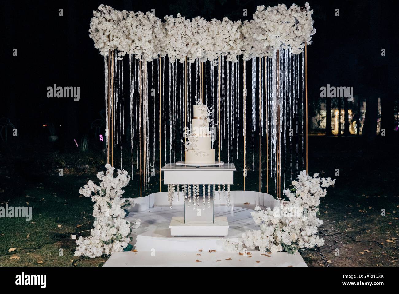 Wedding setup with three-tier white cake with floral accents. Wedding ...