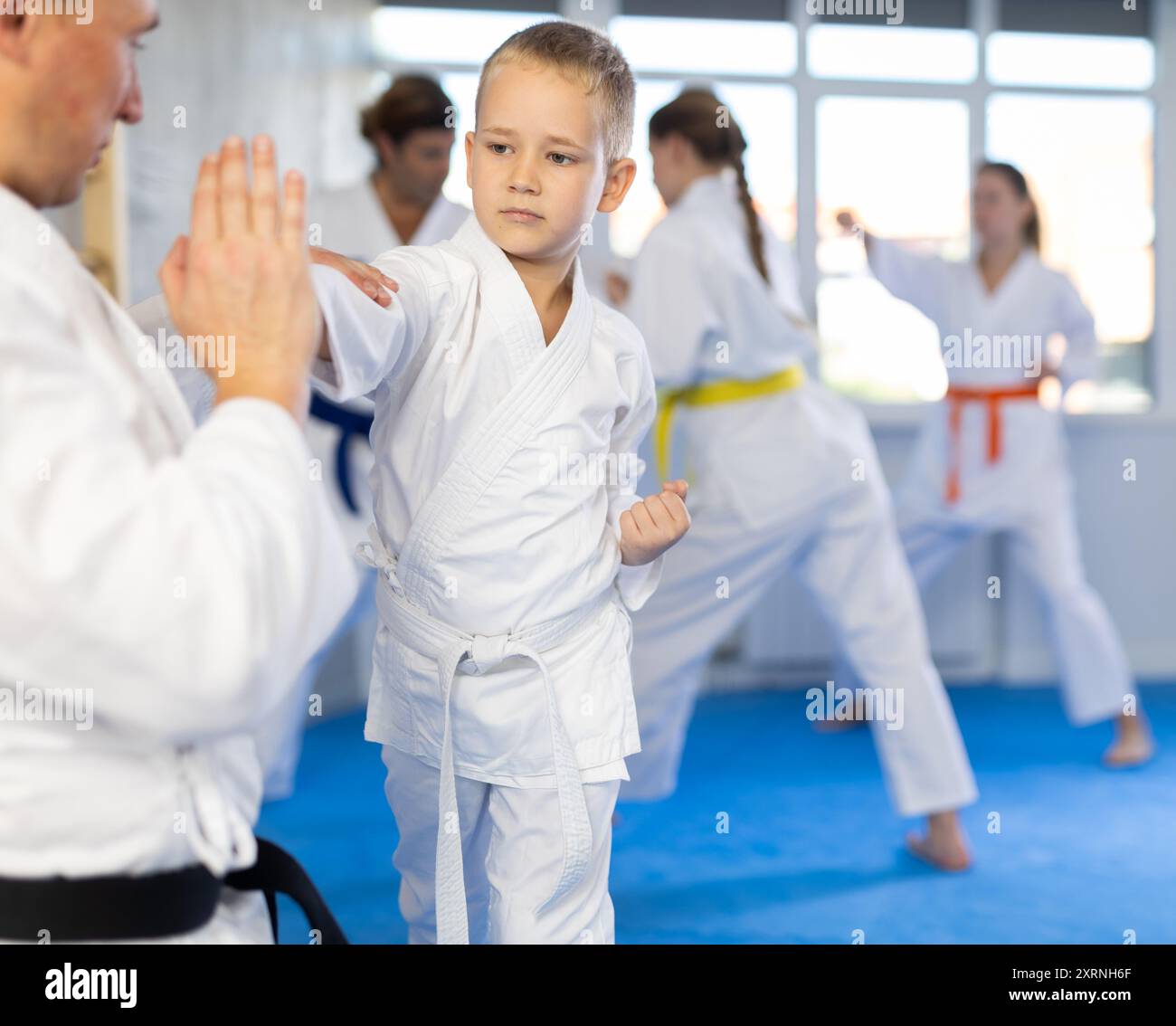 Boy at group training in gym practice karate punch block technique with ...