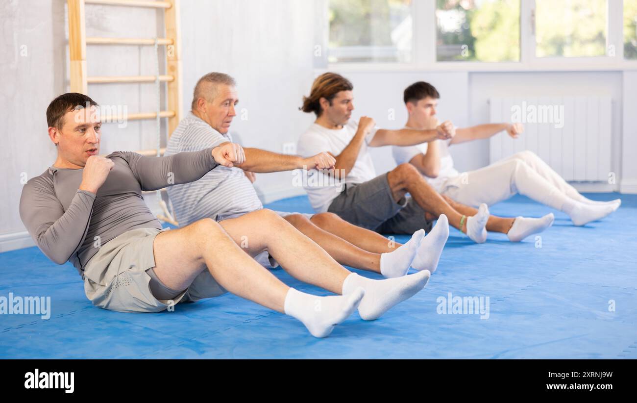 Men pupils performs exercises to strengthen press and improve accuracy ...