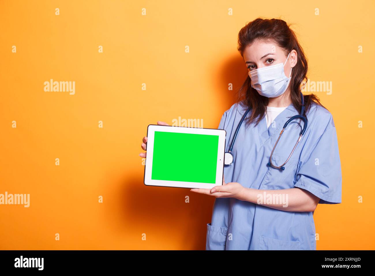 Nurse practitioner with face mask horizontally holding tablet with ...