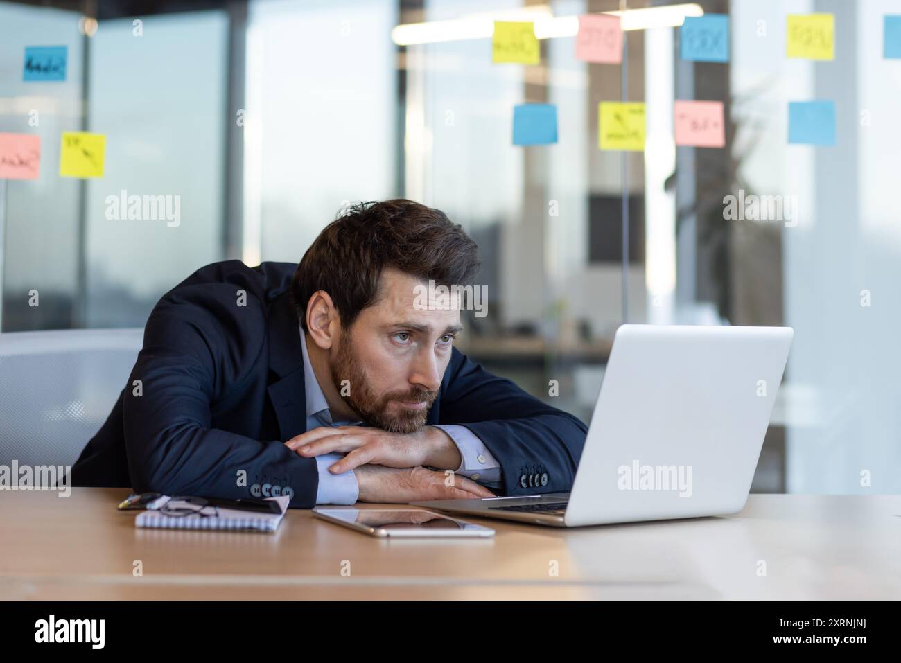 Stressed businessman resting his head on hands on desk with laptop in ...