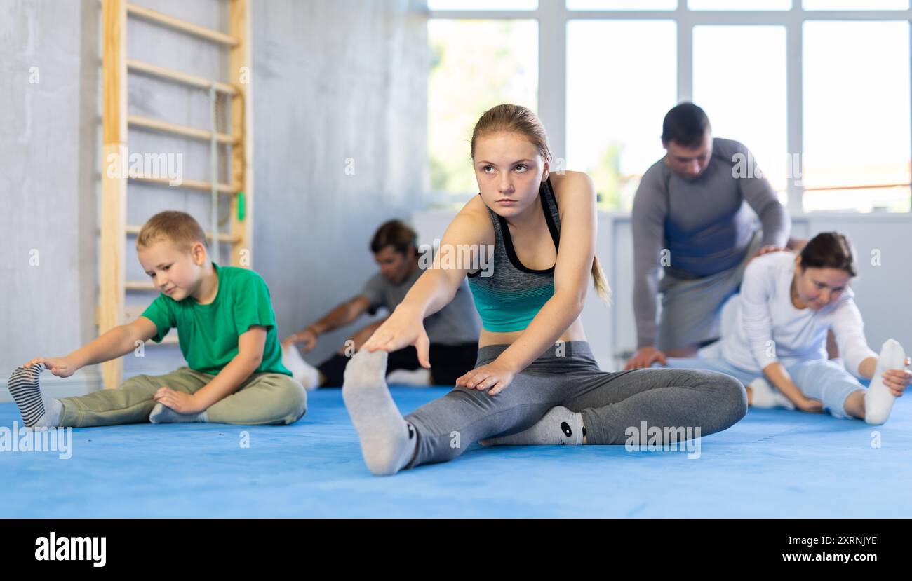 Parents with children family perform warm-up exercises and legs ...