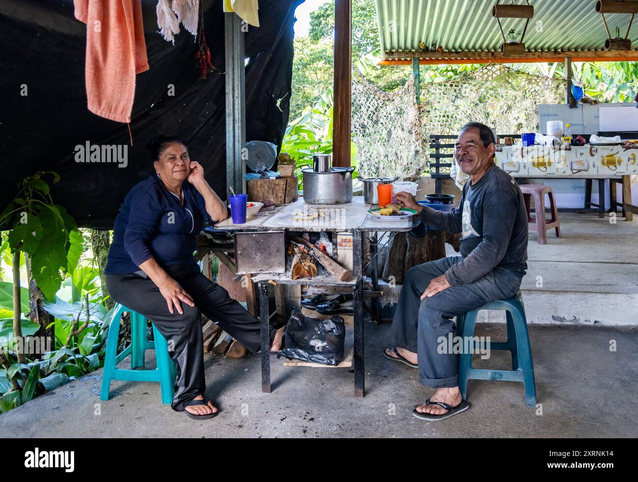 An old Guatemalan couple sitting and eating by their stove top at their ...