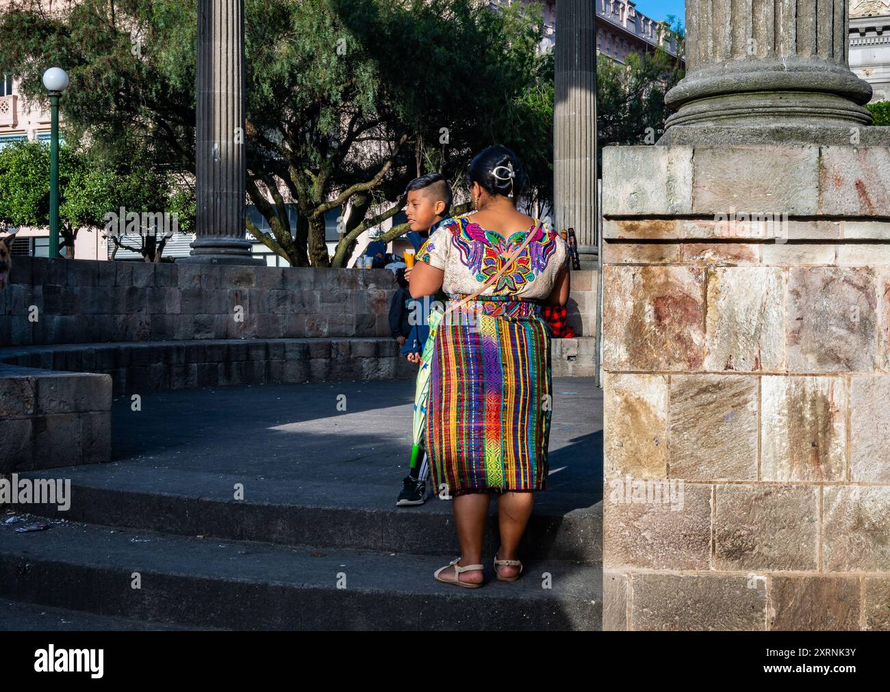 A Guatemalan woman dressed in colorful traditional clothing and her son ...