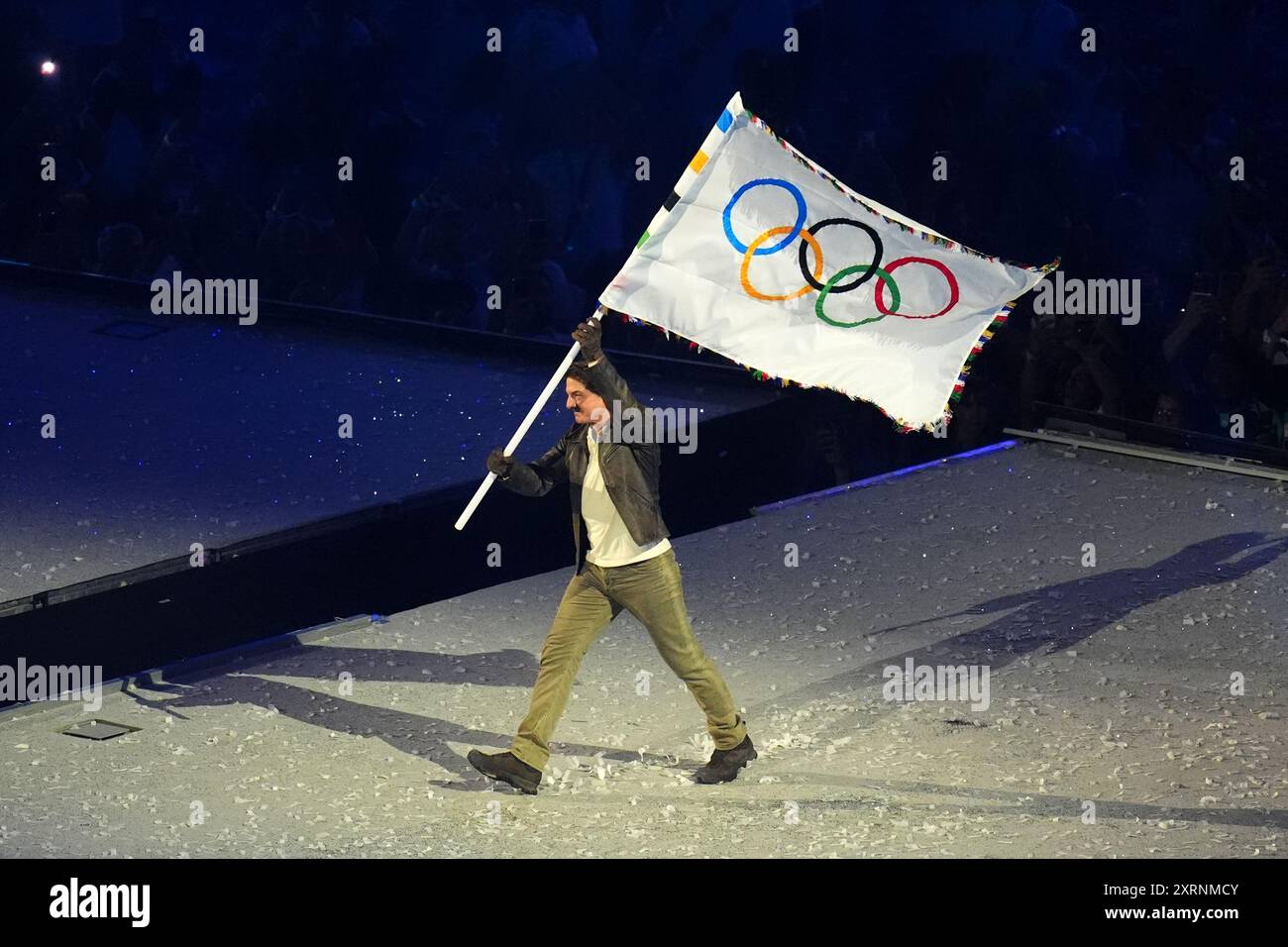 Tom Cruise leaves the stadium with the IOC flag during the closing ...