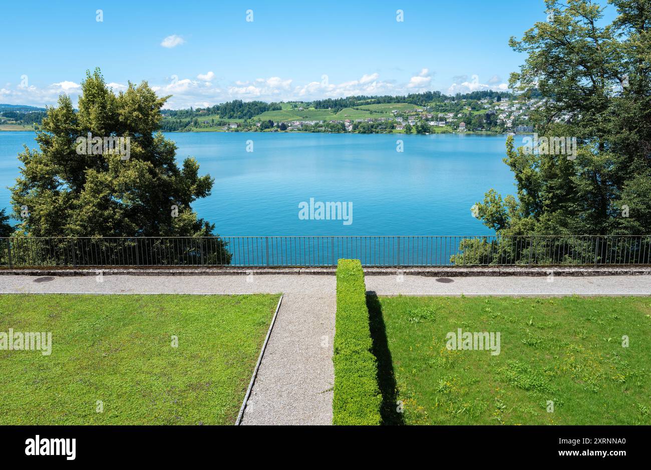 Tranquil lakeside scene in Rapperswil with lush greenery and blue sky ...