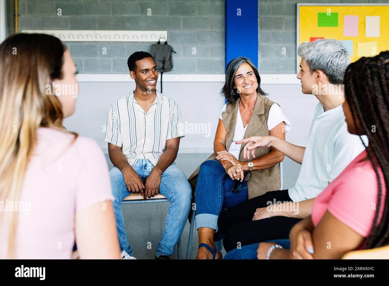 Young group of teenage students discussing in classroom with teacher ...