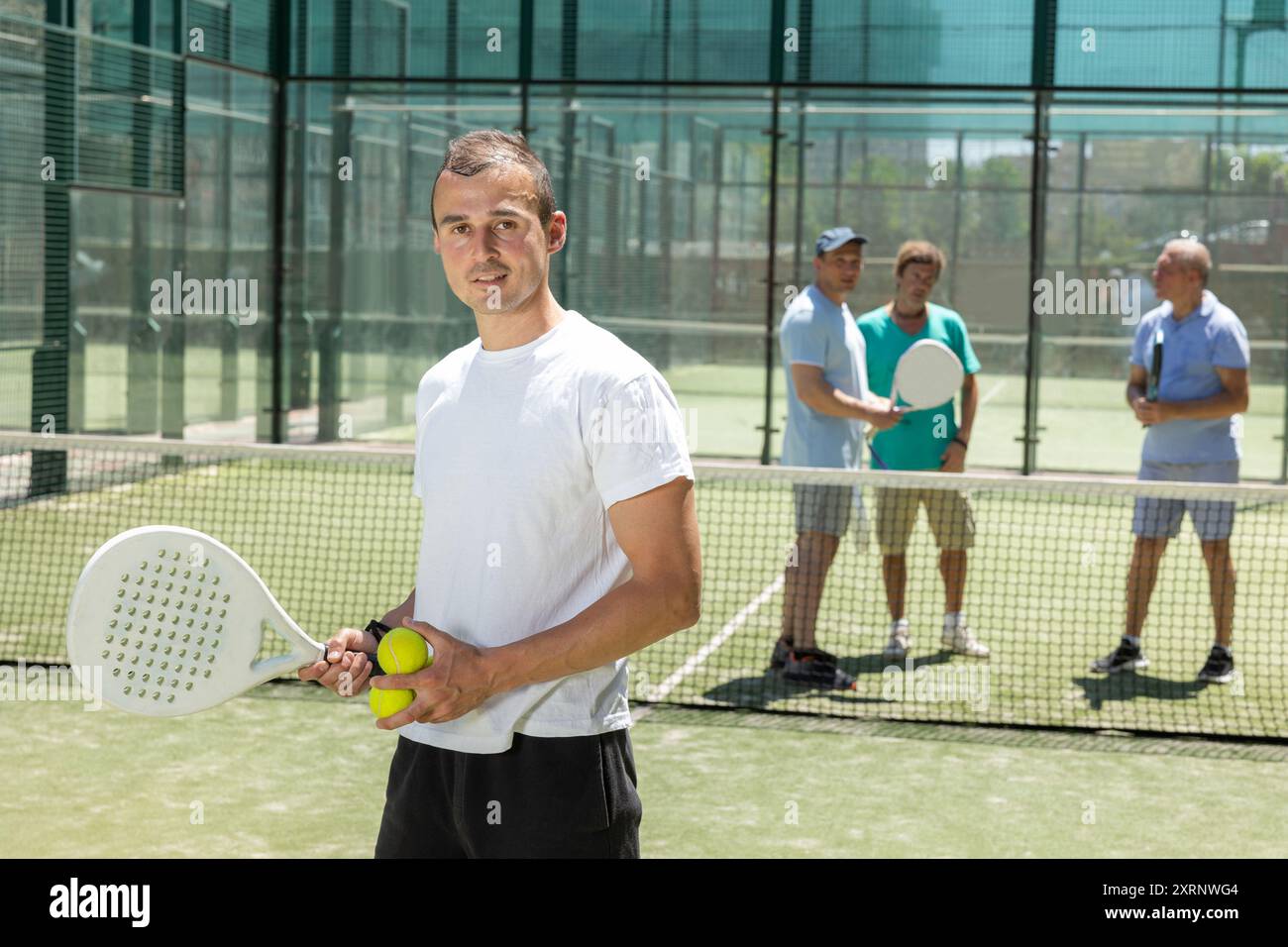 Portrait of sporty male padel player with a racket and ball in his ...