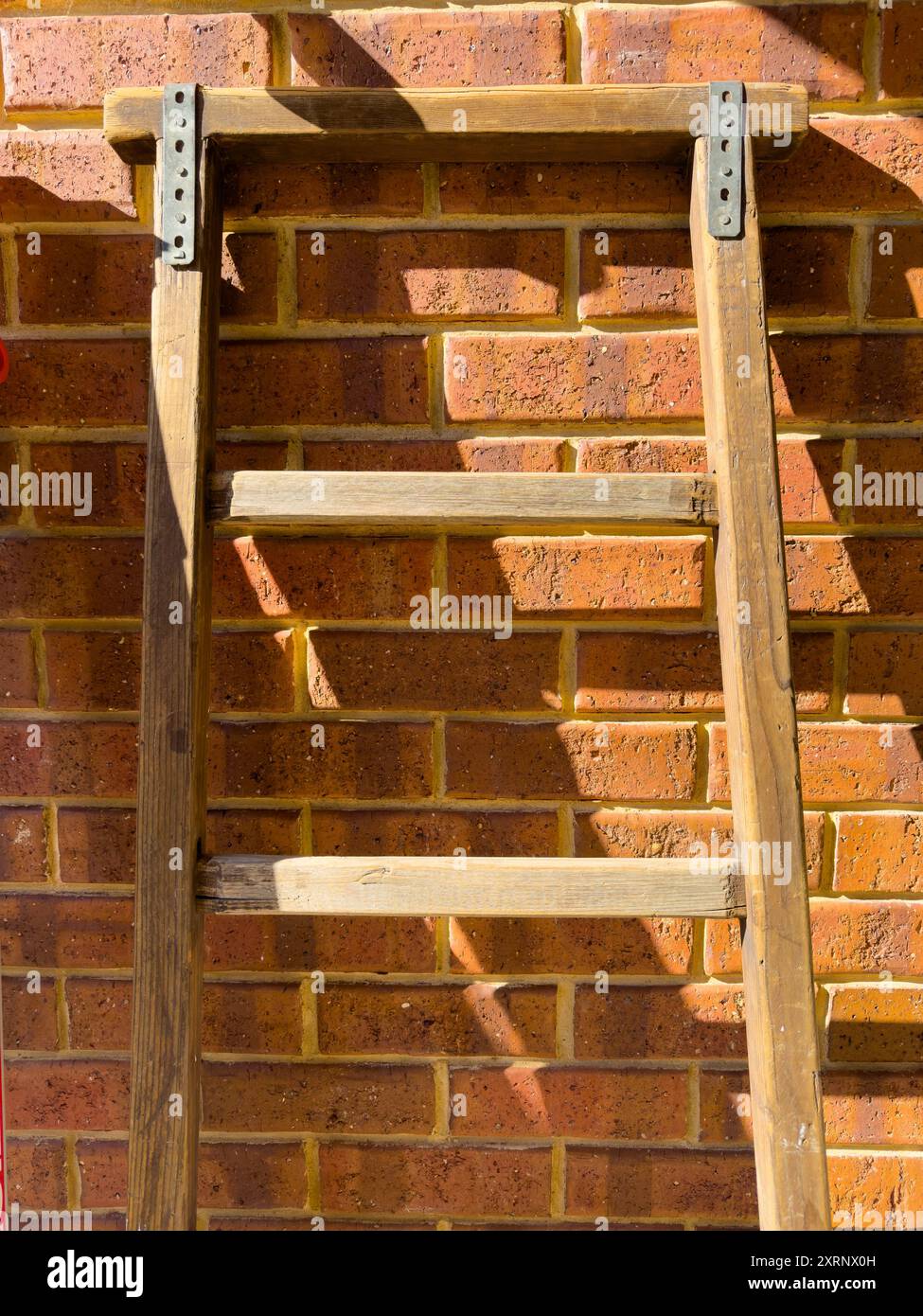 Vintage wooden ladder leans against a classic red brick wall in high ...