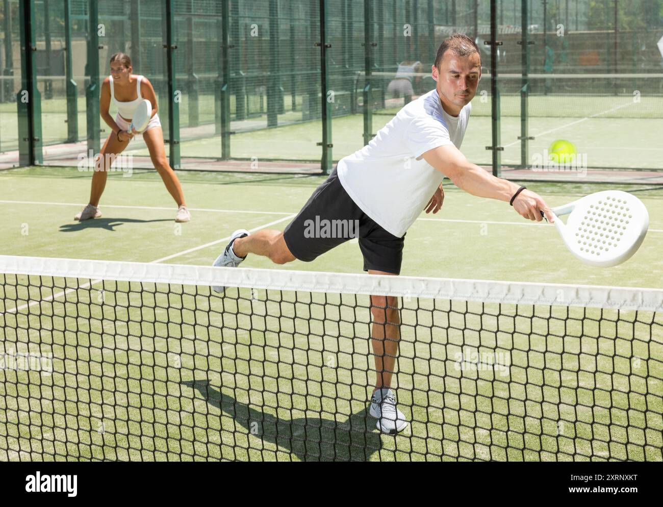 Active woman and man tennis players with rackets playing padel on an ...