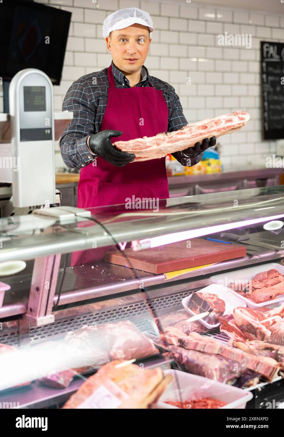 Diligent male butcher offering to sell big piece of beef beef in ...