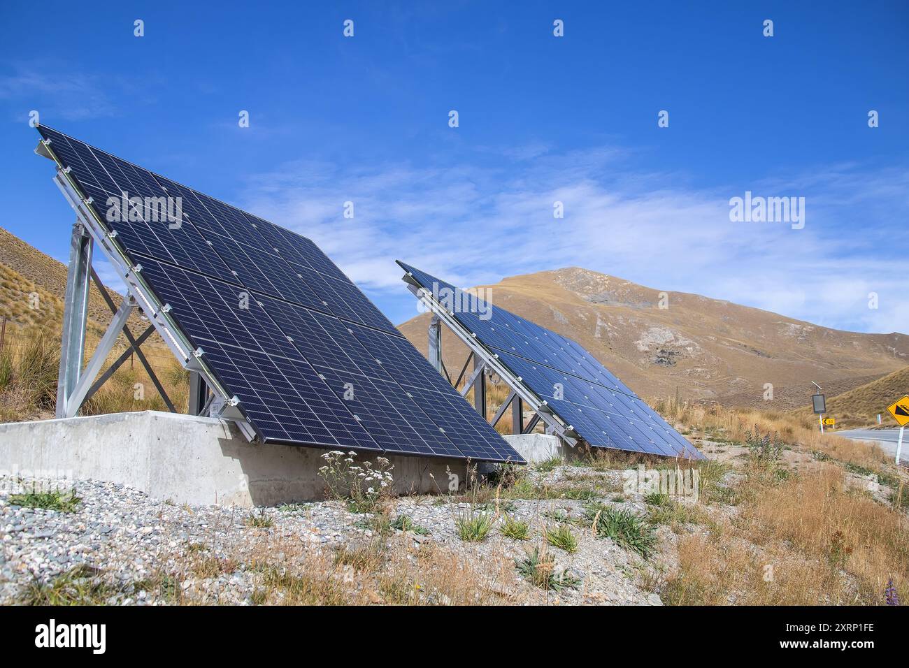 Solar panels are installed on a mountainside next to the road ...