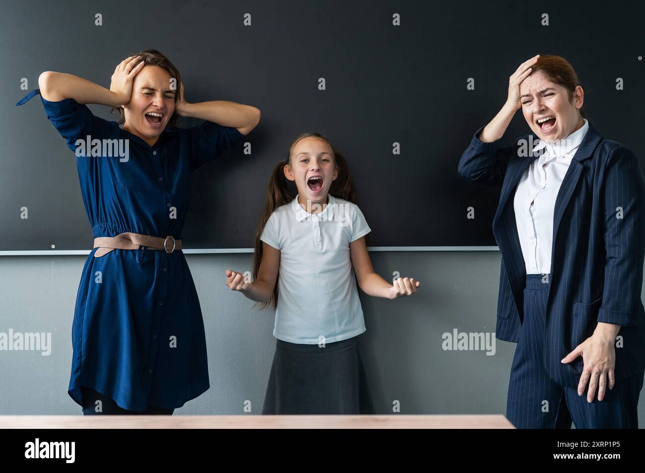 Female teacher, schoolgirl and her mother yell at each other while standing at the blackboard ...