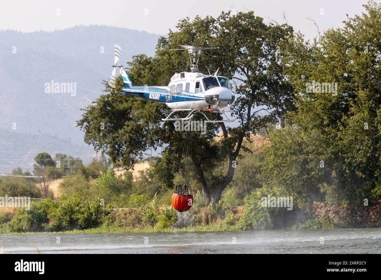REDDING CALIFORNIA – AUGUST 10, 2024 –A Bell UH-1 helicopter dipping ...