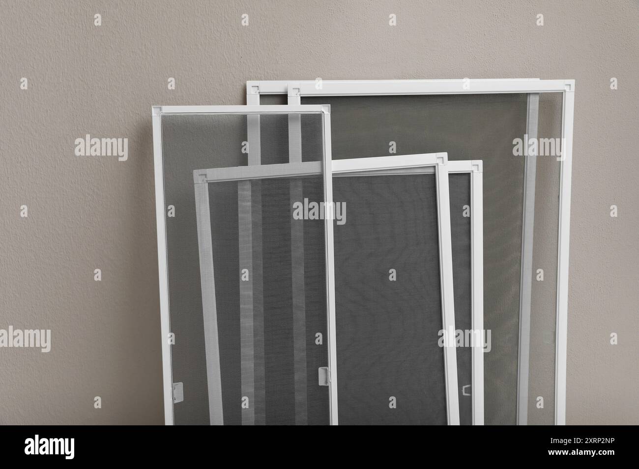 Set of window screens near beige wall Stock Photo - Alamy