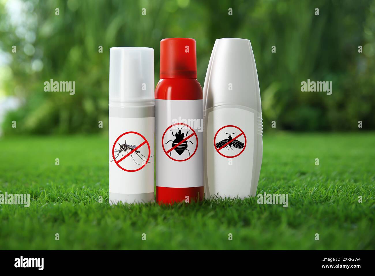 Different insect repellents in spray bottles on green grass outdoors ...