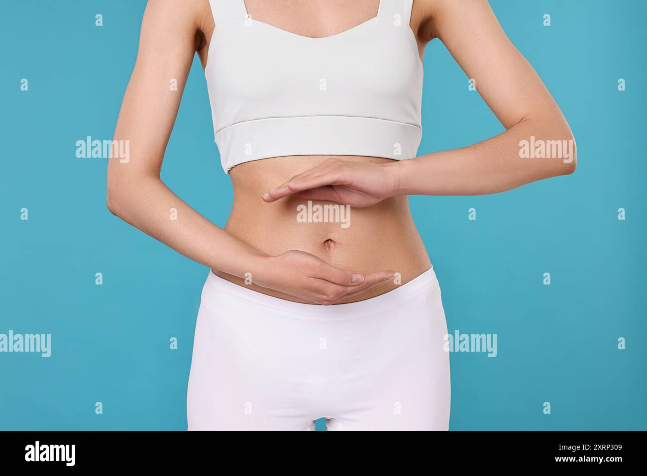 Healthy digestion. Woman holding something near her belly on light blue ...