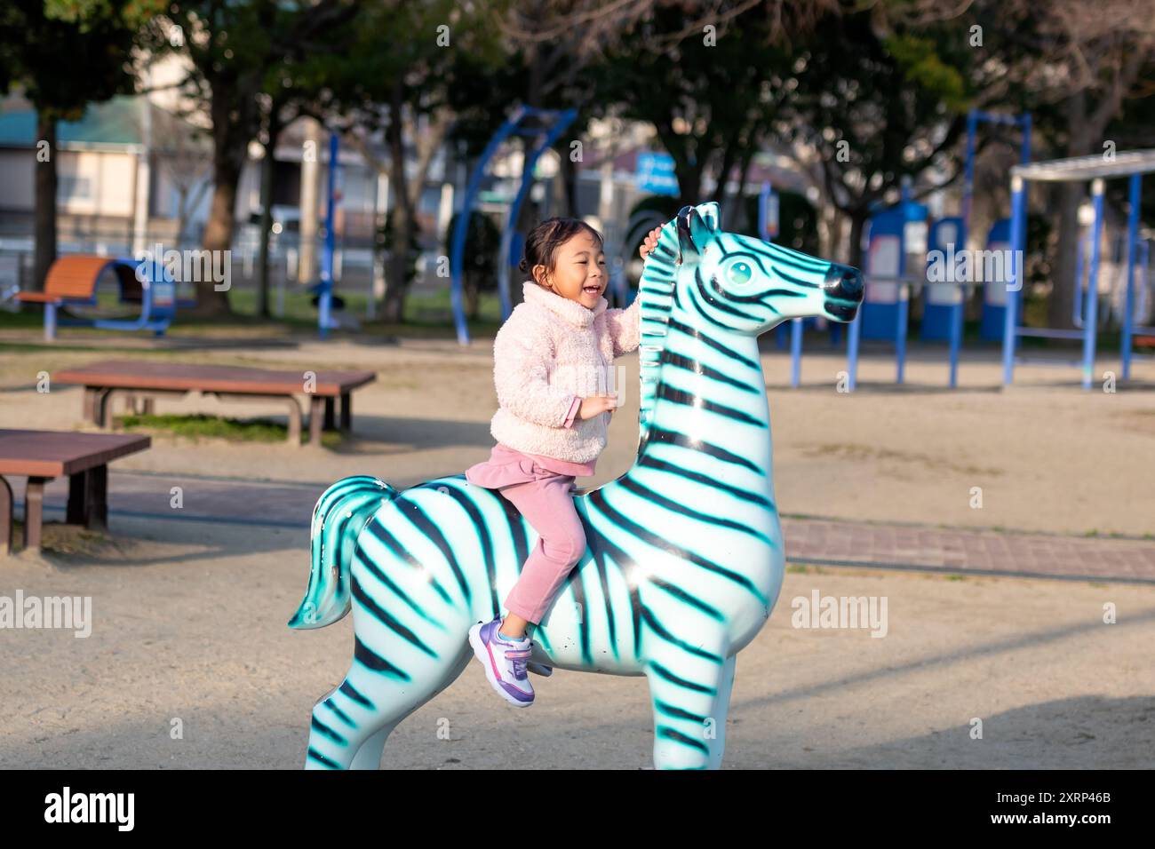 A girl riding a zebra sculpture at a park playground Stock Photo - Alamy