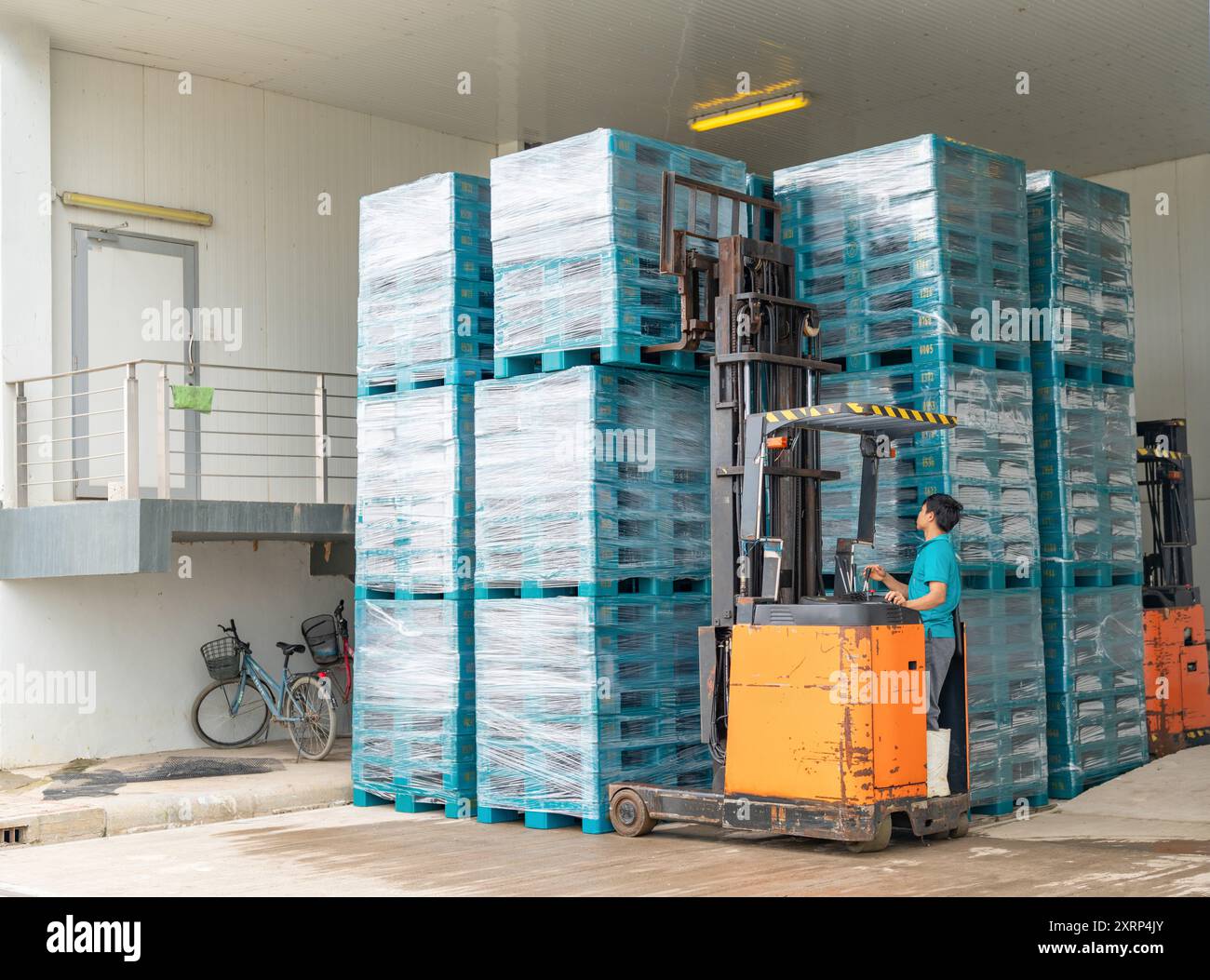 Worker drive electric forklift lift pallet stack up to set in factory ...