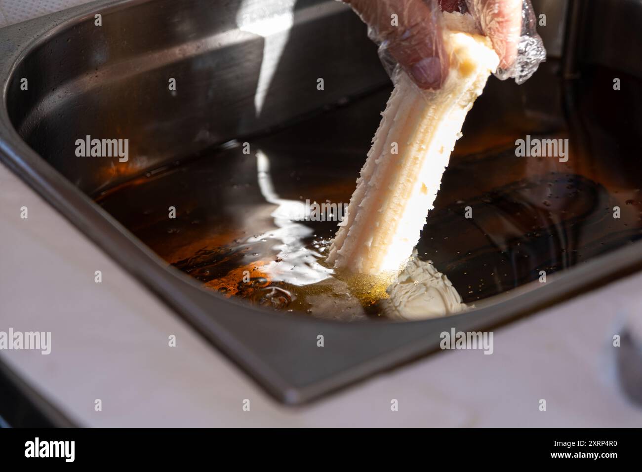 Woman putting raw churros dough into hot oil to fry it 2 Stock Photo ...