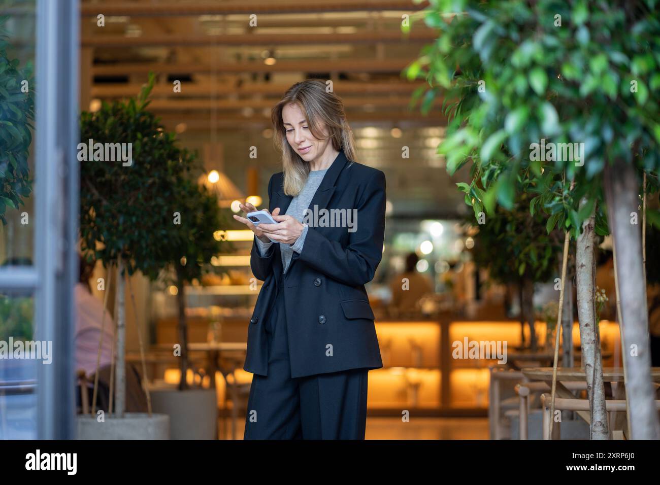 Focused woman modern cafe owner using phone typing message, examines ...