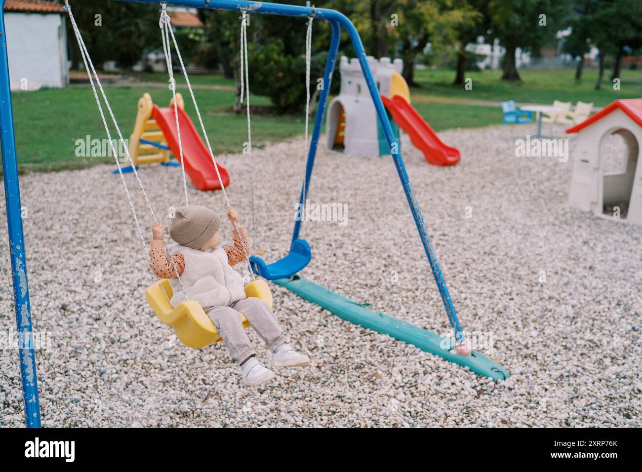 Little girl swings on a rope swing at the playground and looks away Stock Photo - Alamy
