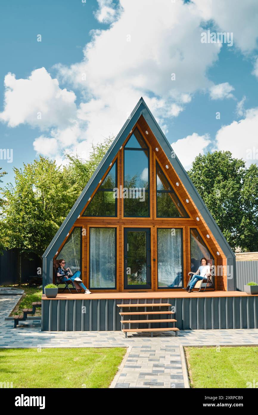Mother and daughter sitting on a folding chairs on the terrace of a ...