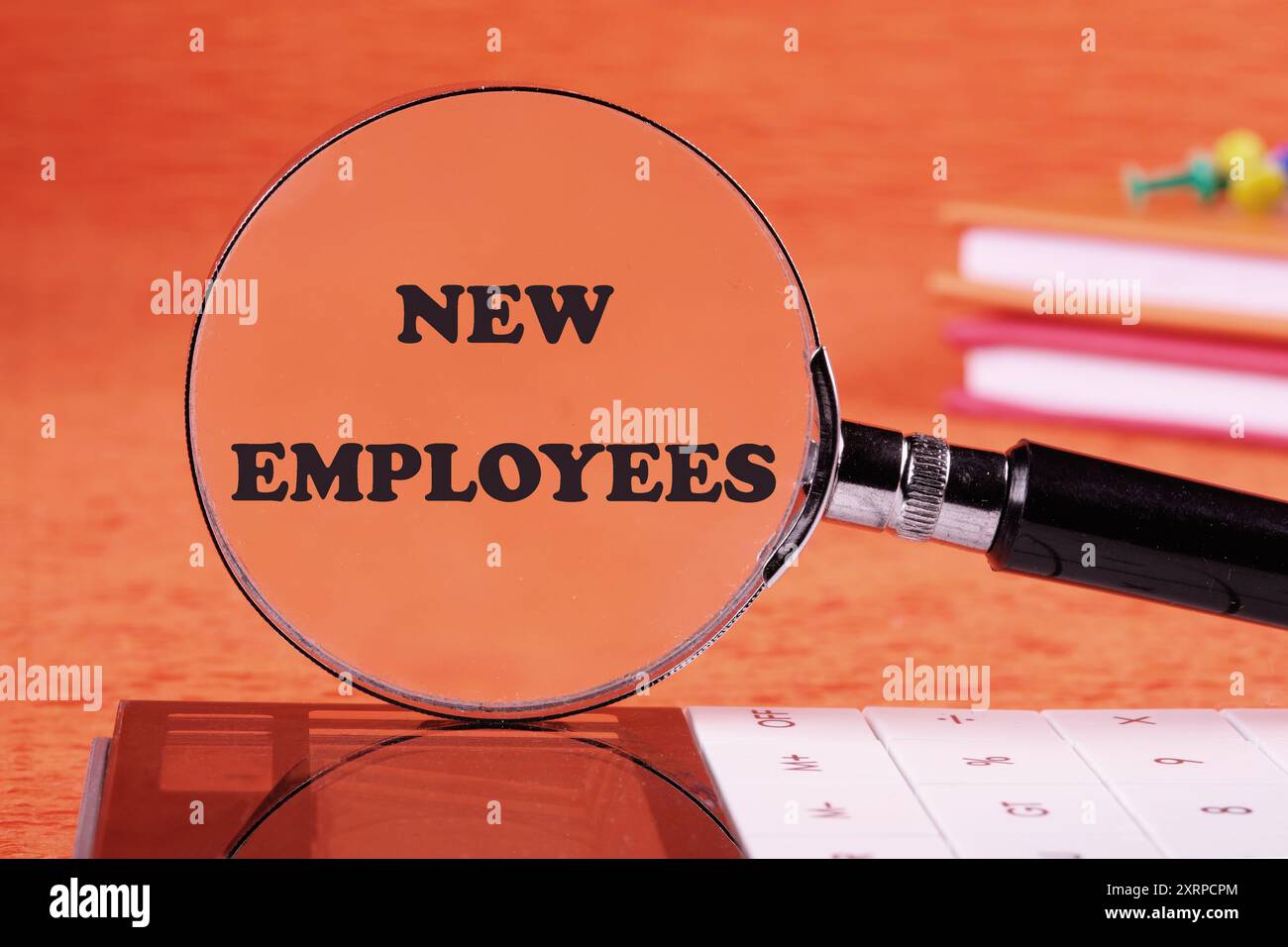 Concept words NEW EMPLOYEES through a magnifying glass on an orange ...