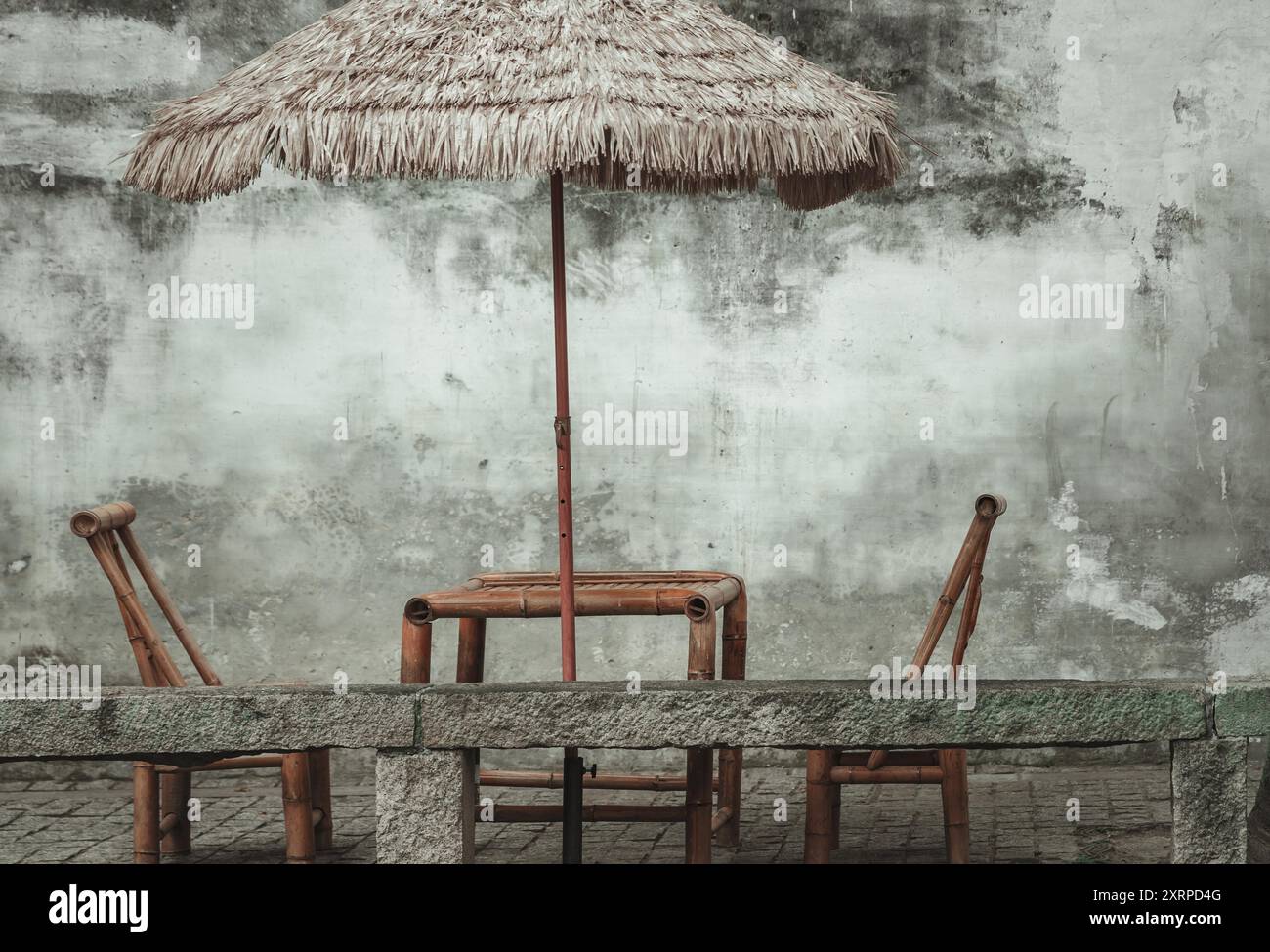 A thatched umbrella shades a patio set made of bamboo and stone Stock ...