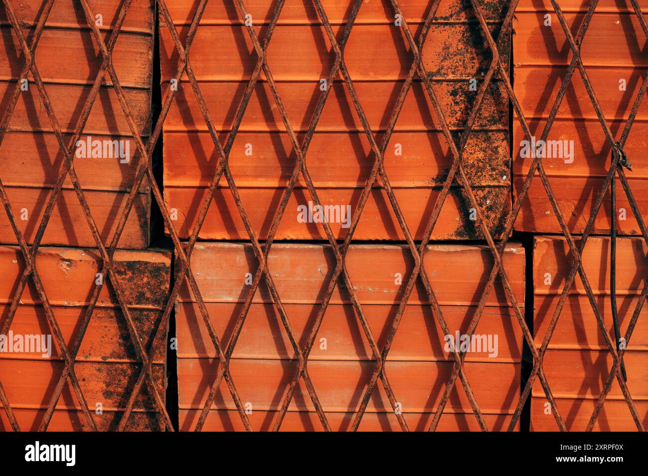 Pile of clay construction blocks behind worn rusty fence as background ...