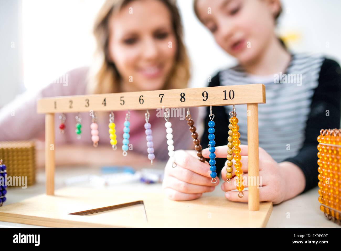 Hardworking teacher learning with young schoolgirl in classroom ...