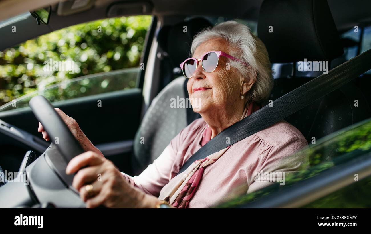 Happy senior woman driving car alone, enjoying car ride. Safe driving ...