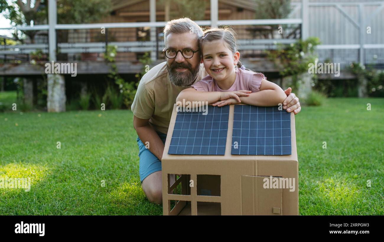 Dad and girl plying with house with solar panels on roof, learning ...