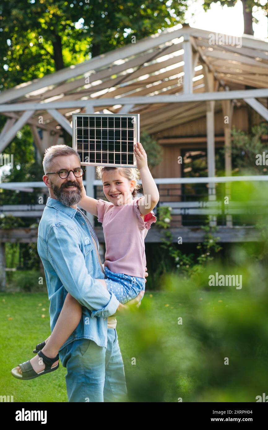 Dad and girl in garden, holding model of solar panel. Sustainable ...