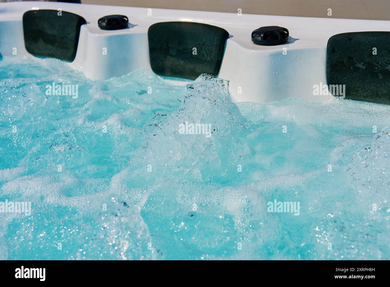 Close-up shot bubbling water in hot tub with headrests. Blue water in ...