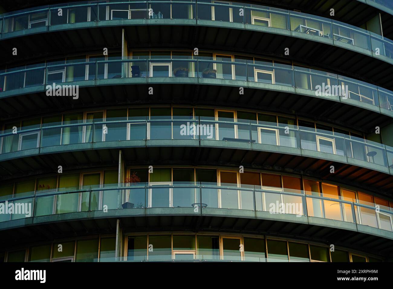 Modern apartment building with curved glass facade. Contemporary architectural design. European ...