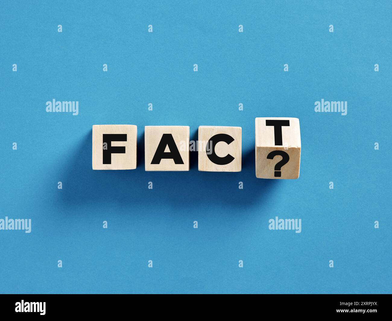 Four wooden cubes with fact and question mark sign on blue background ...