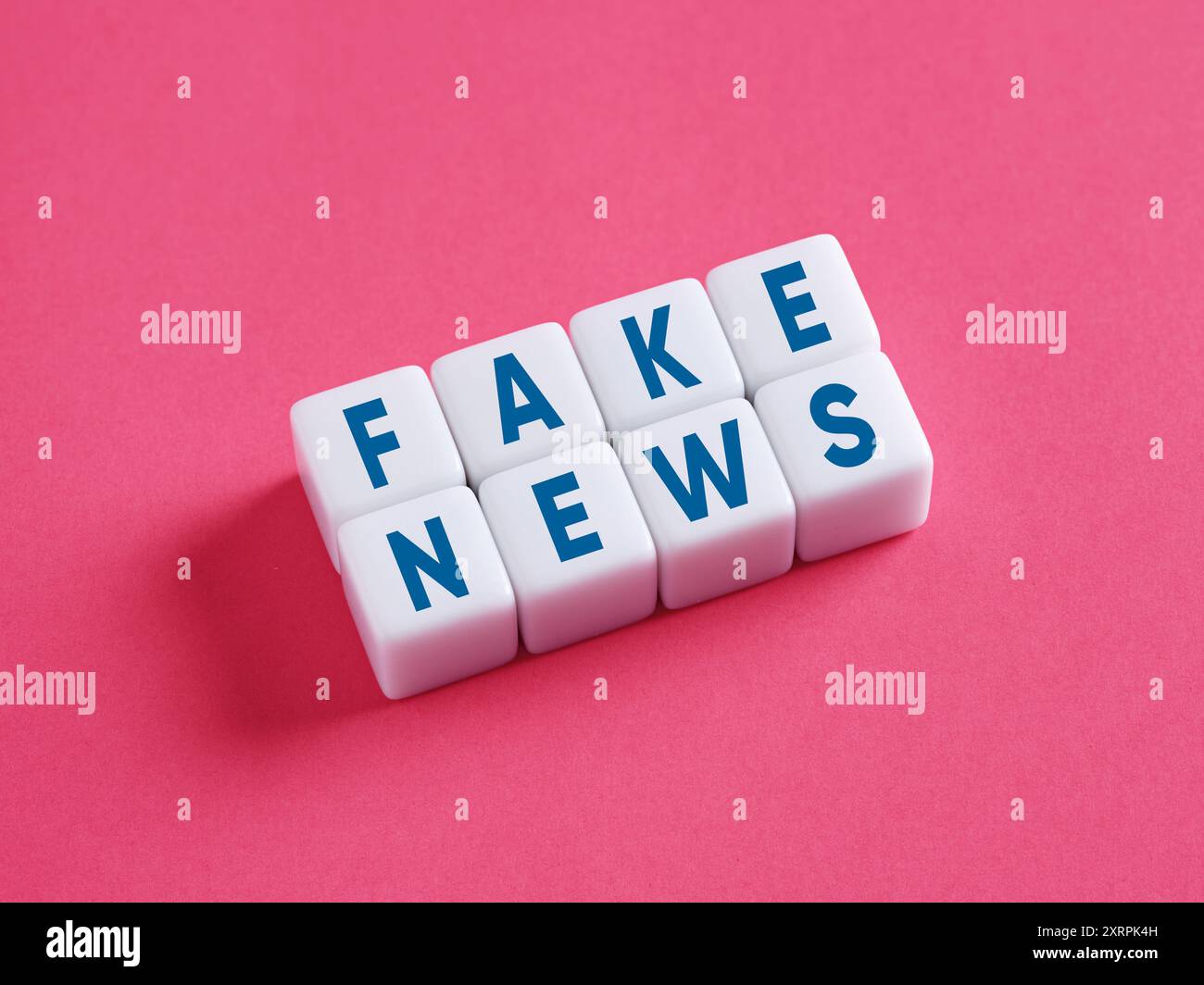 White letter dice forming the words fake news on a pink background ...