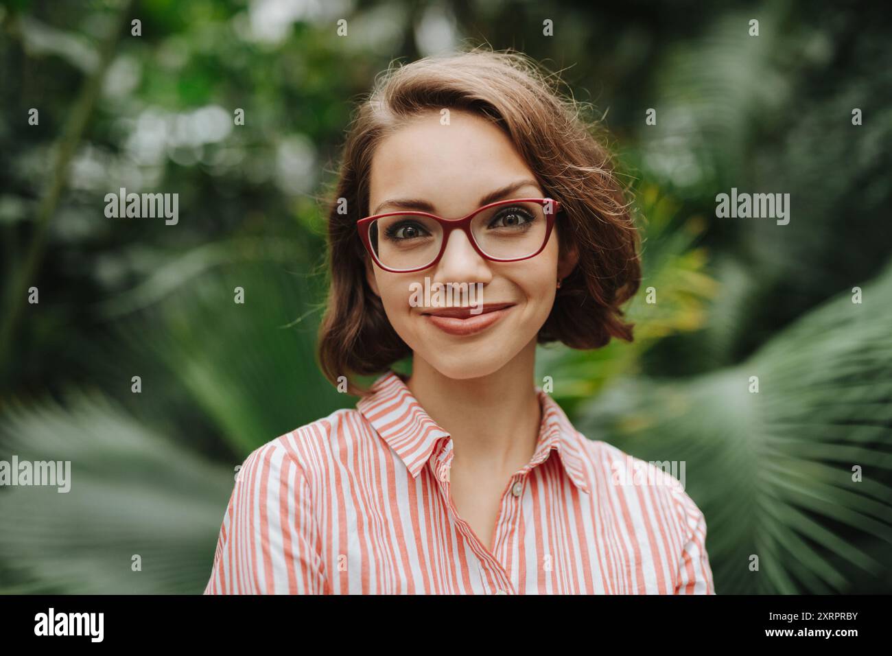 Beautiful woman standing in botanical garden, in the middle of lush ...