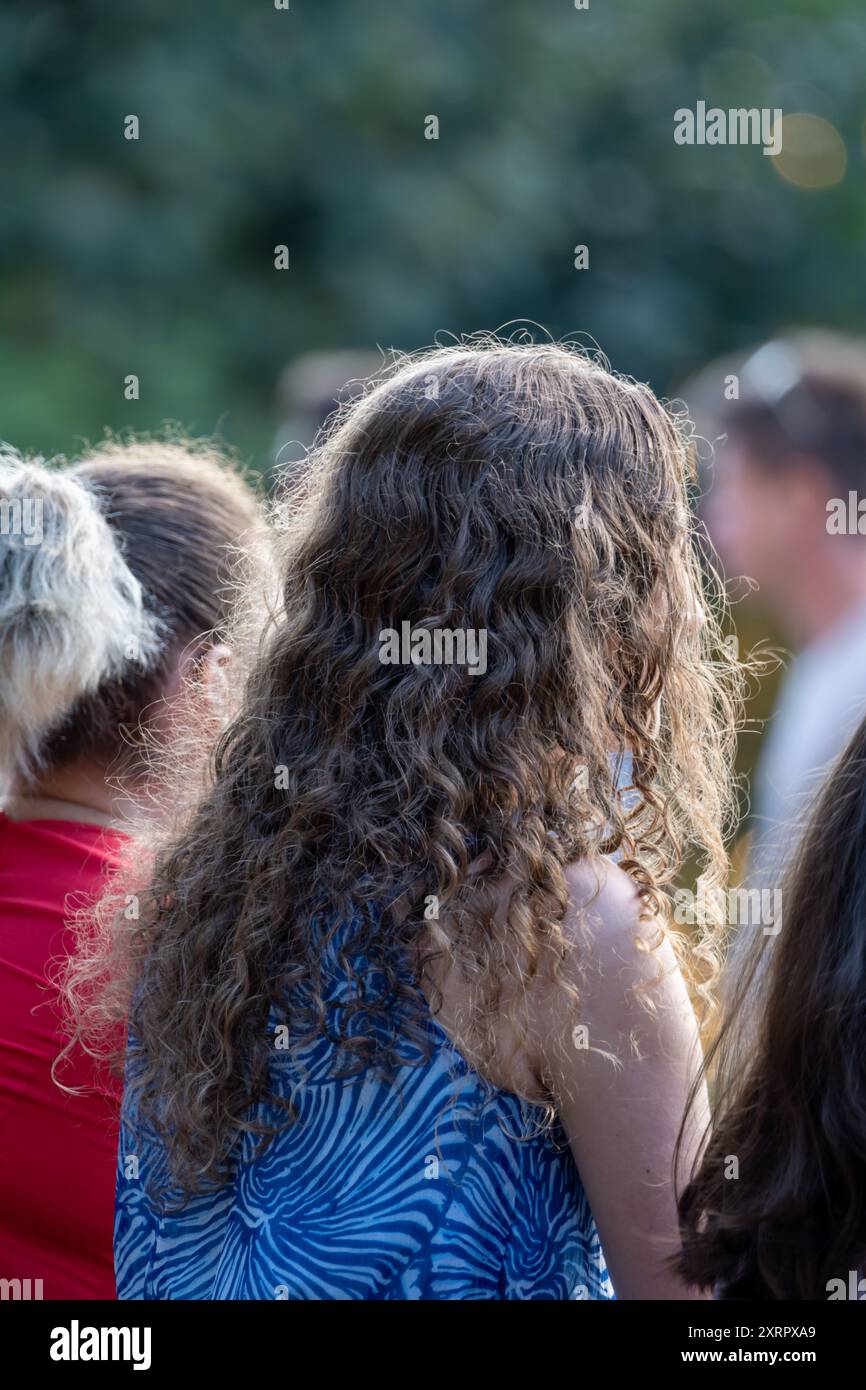 Portrait of a woman sitting in the crowd. Real people. View from behind ...