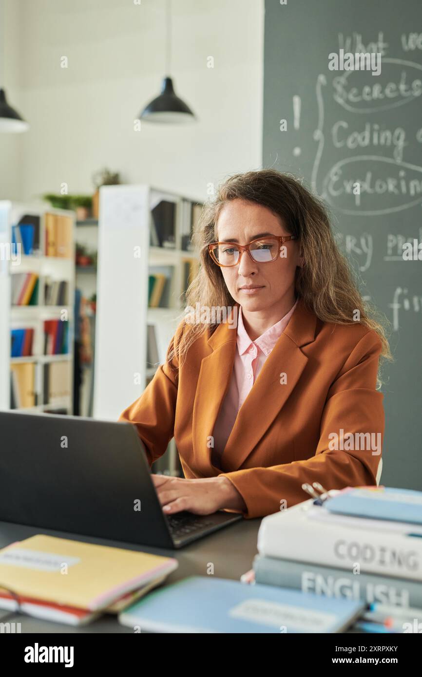 Teacher Wearing Glasses using Computer Stock Photo - Alamy