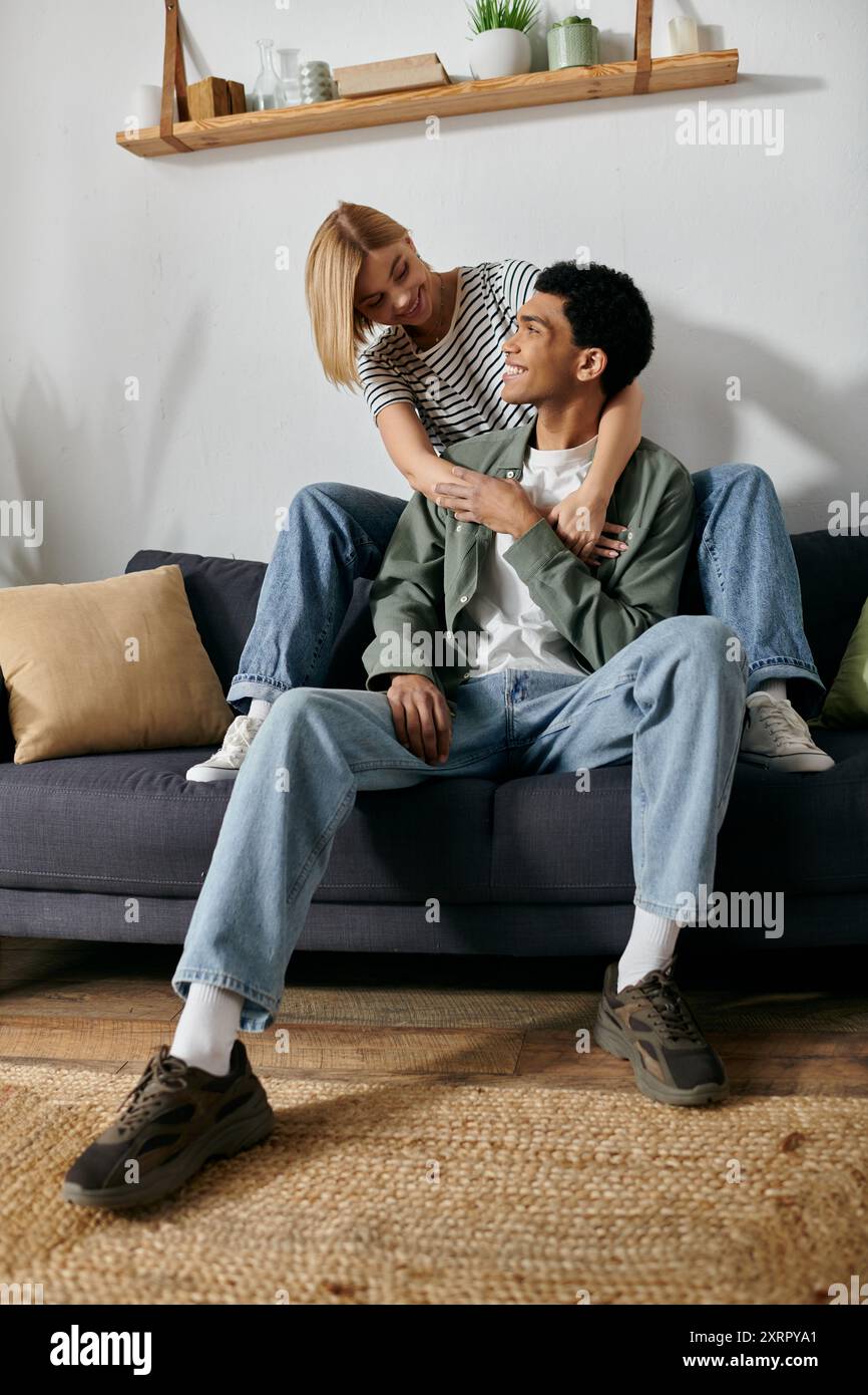 A young couple, a man and a woman, cuddle on a sofa in a modern ...