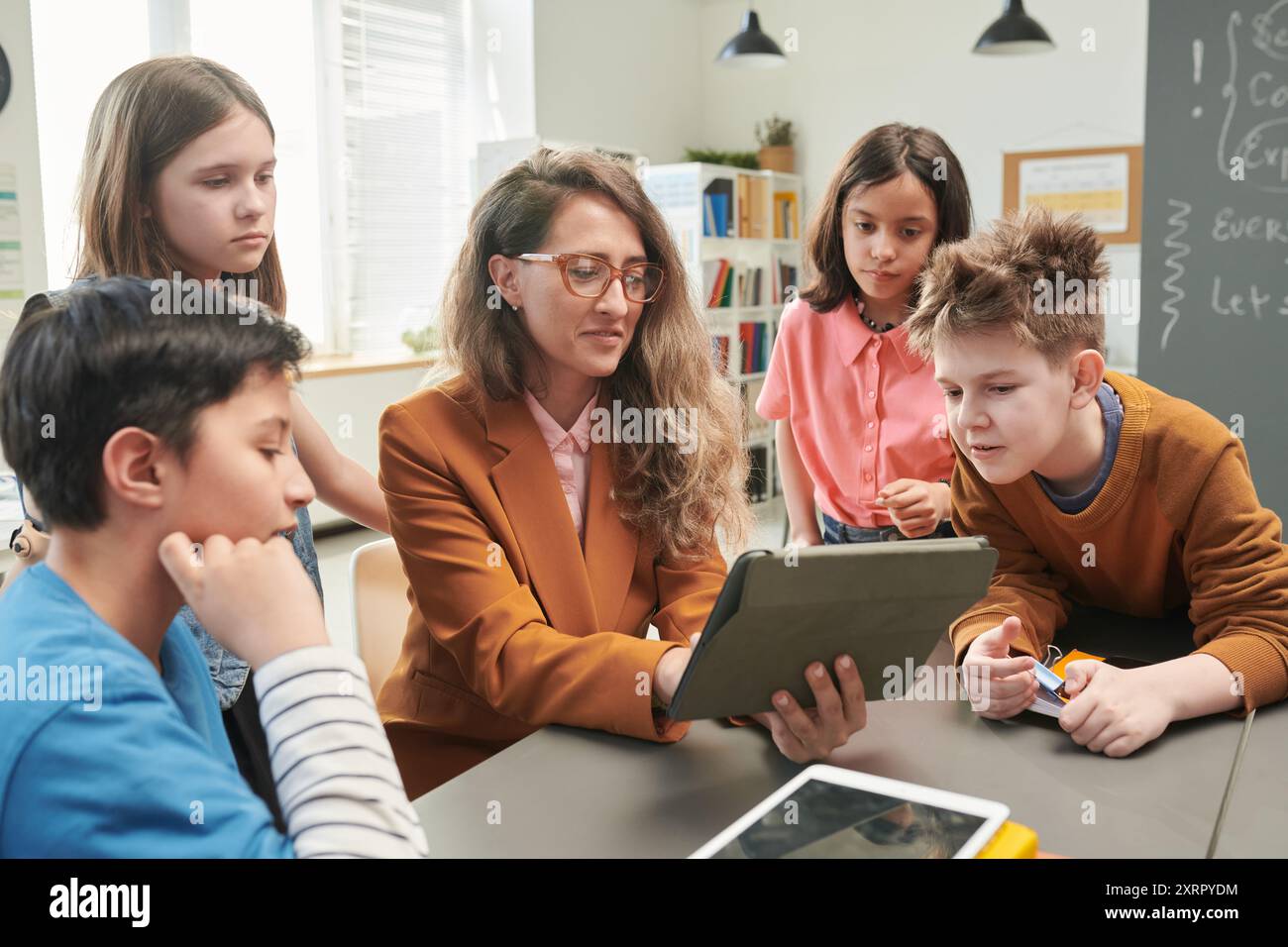 Teacher using Tablet with Group of Children Stock Photo - Alamy