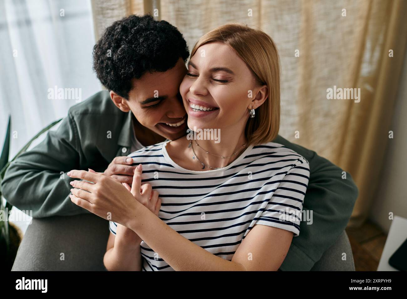 A young, multicultural couple enjoys a moment of intimacy and laughter ...
