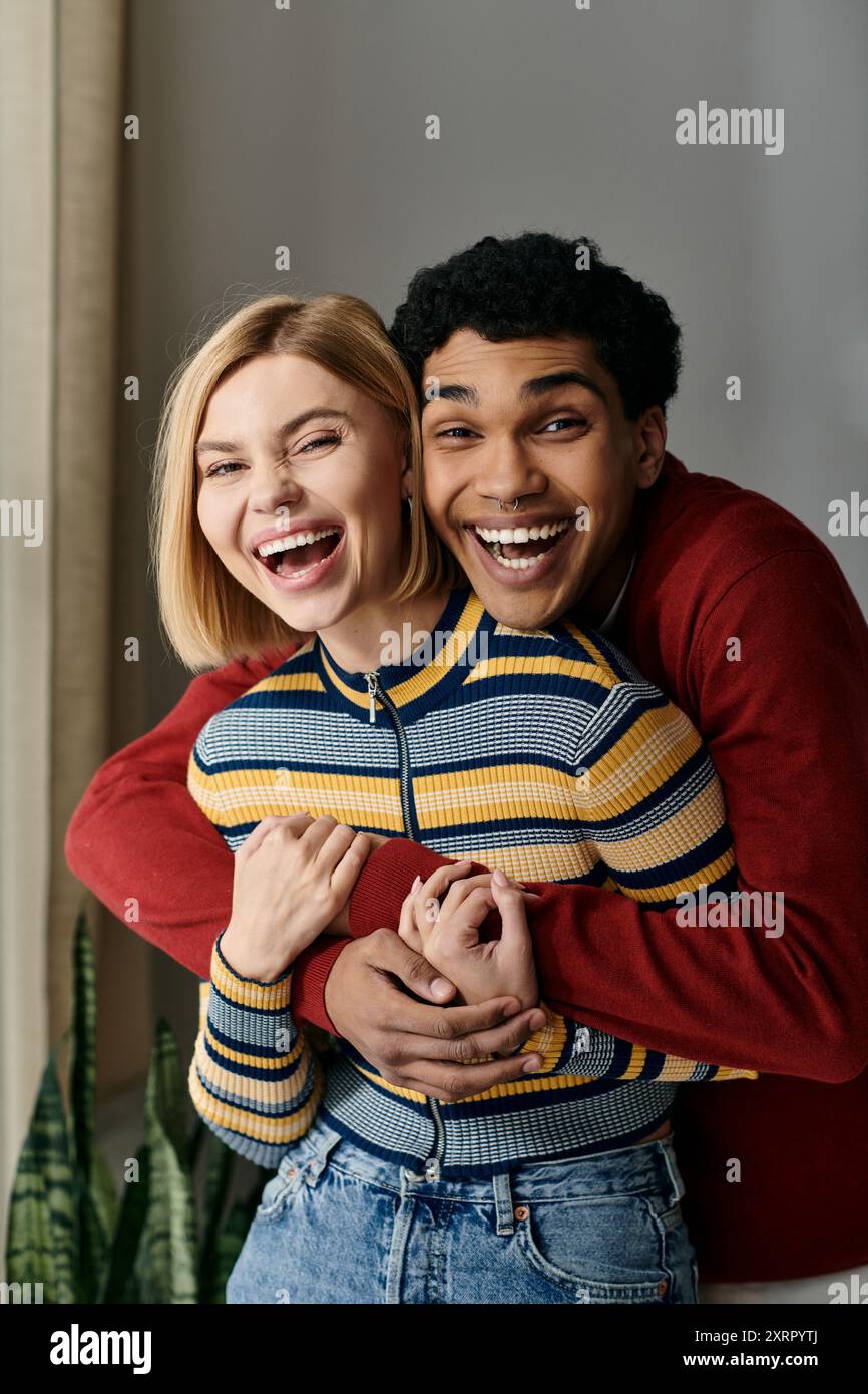 A happy multicultural couple laughs together in a modern apartment ...