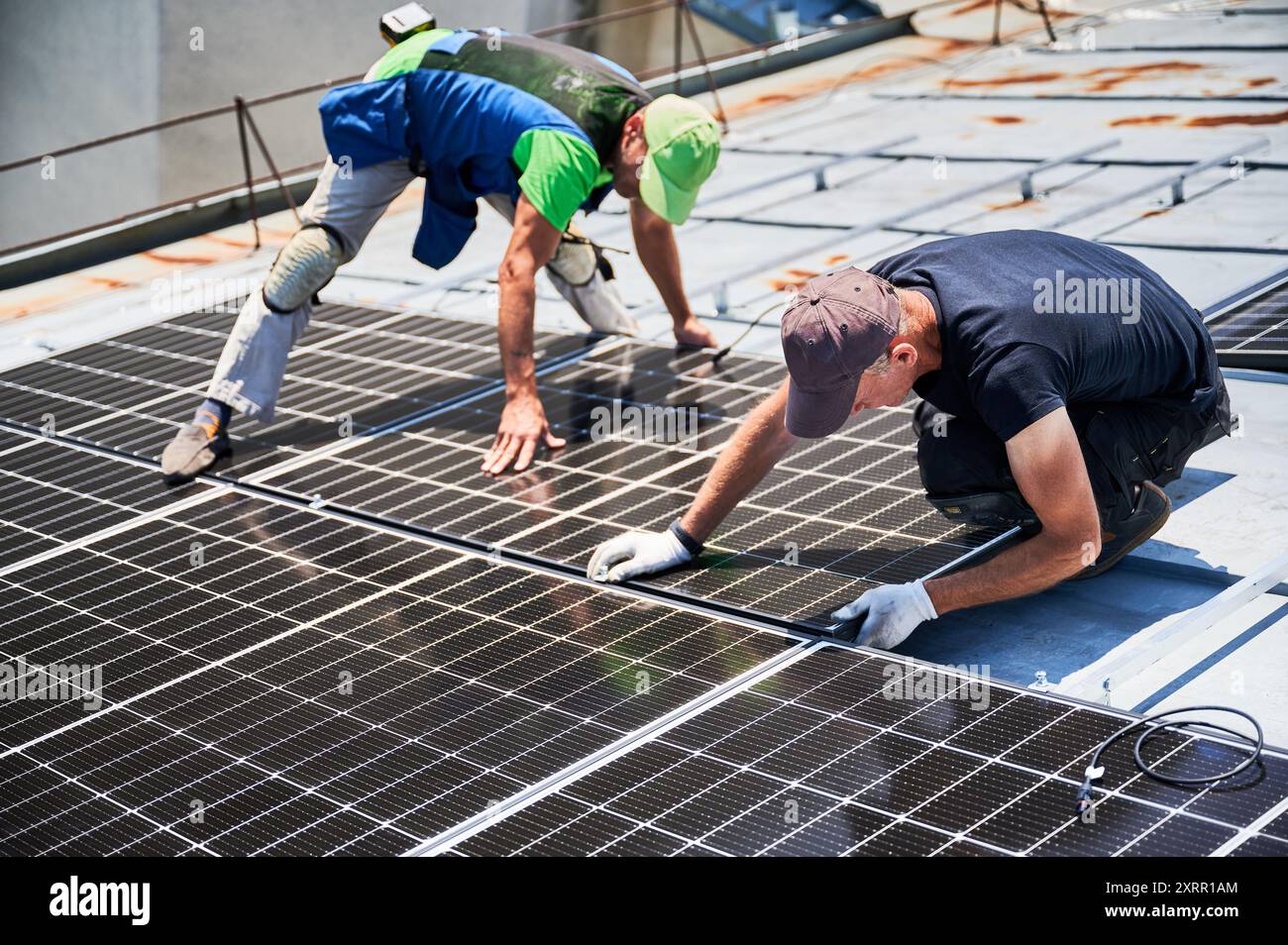 Workers building solar panel system on metal rooftop of house. Two men ...