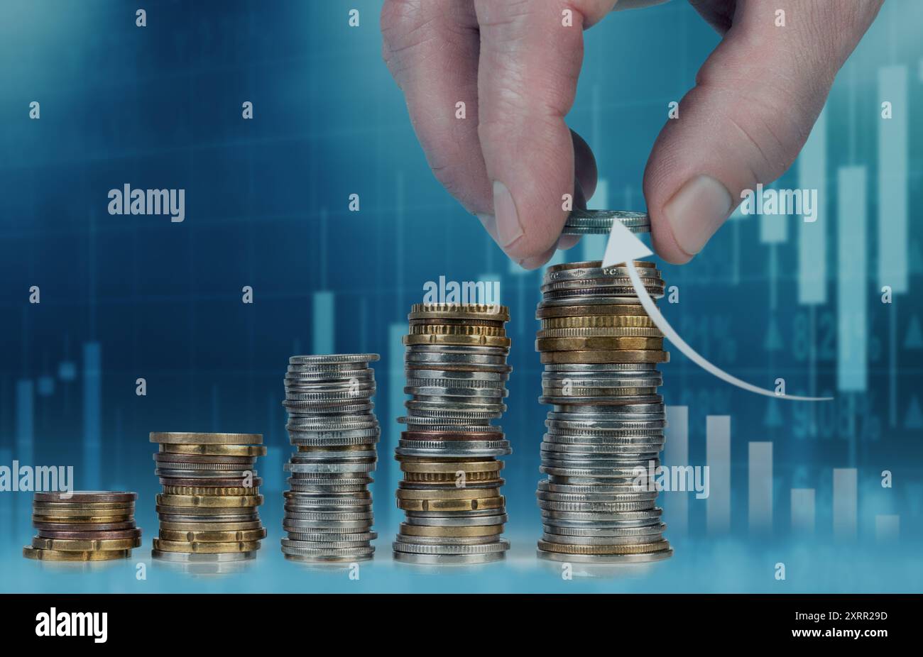 Hand stacking coins against a background of financial graphs ...