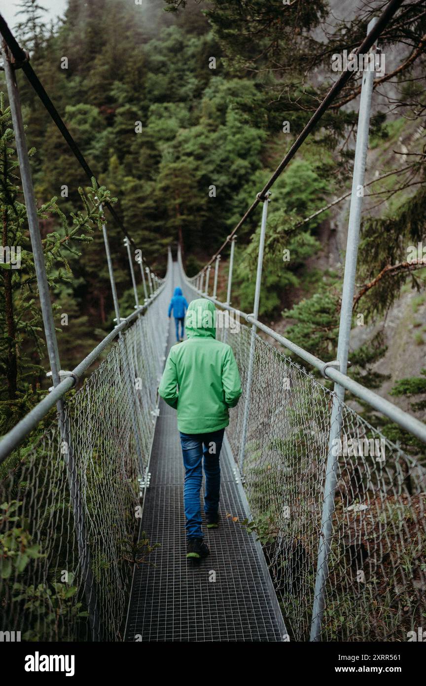 Two boys walk on a suspension bridge in rainy Wallis, Switzerland Stock ...