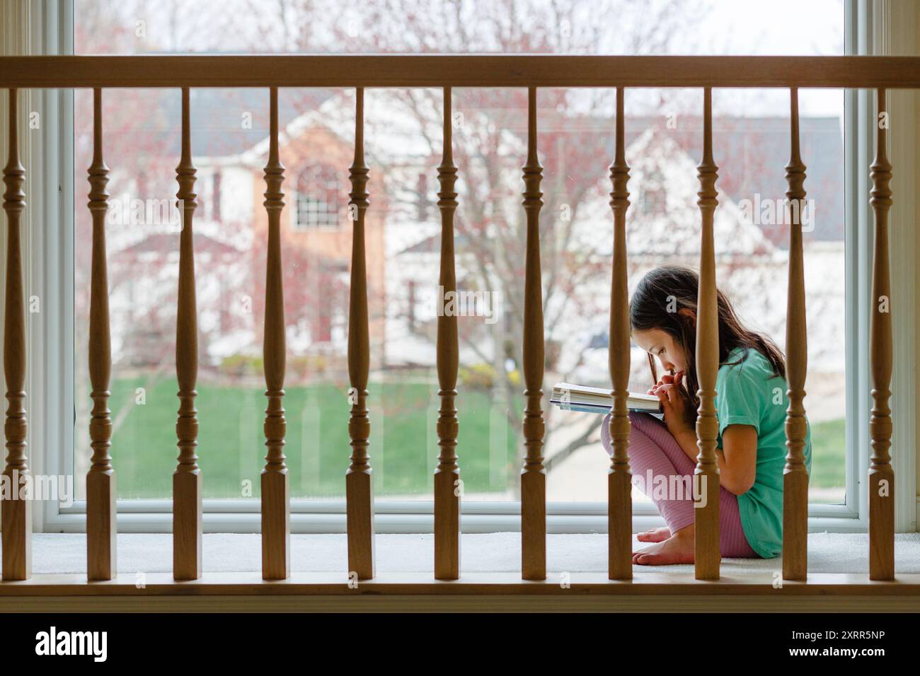 A little girl sits in loft by window reading a book Stock Photo - Alamy
